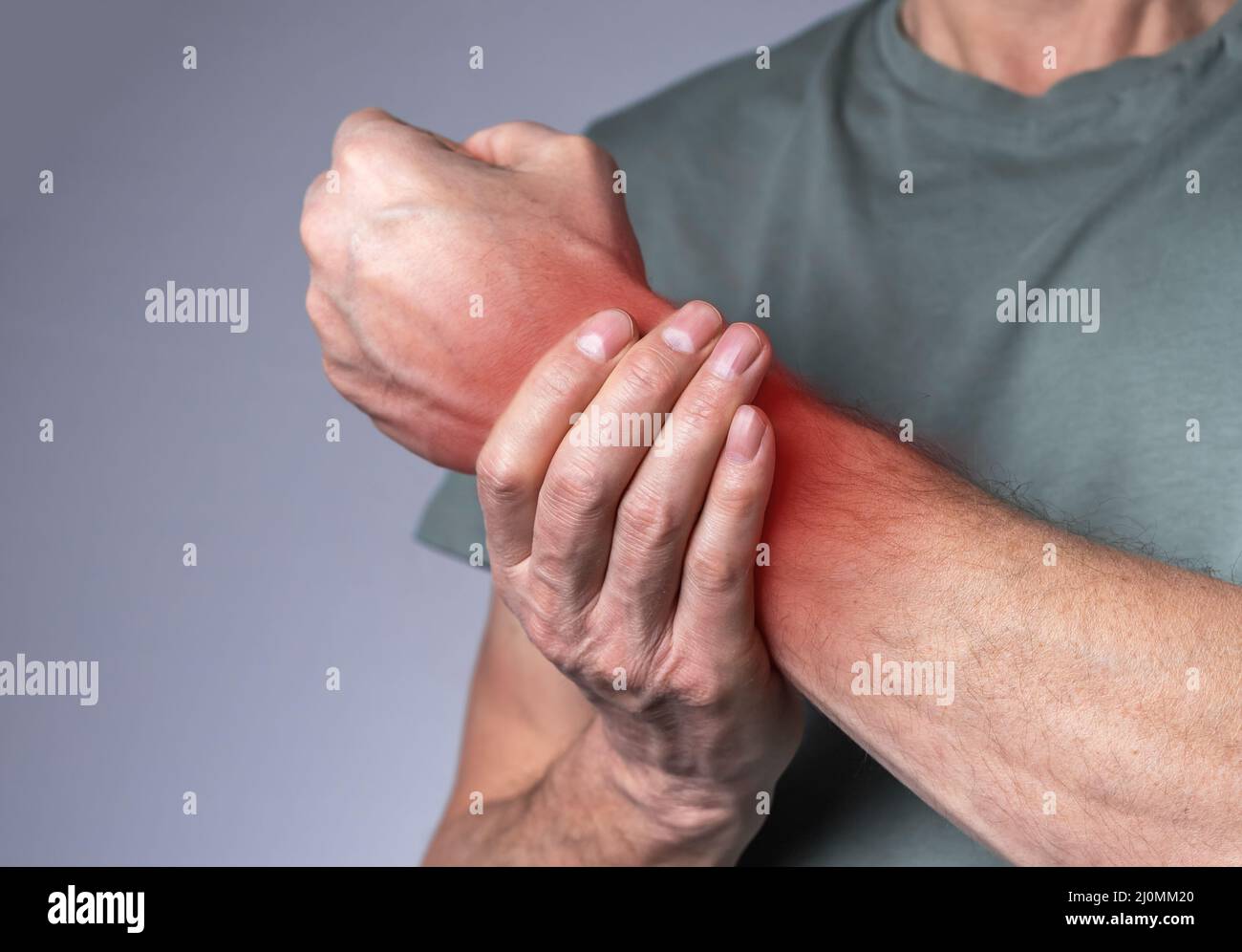 Man suffering from wrist pain and holding painful hand with red spot ...