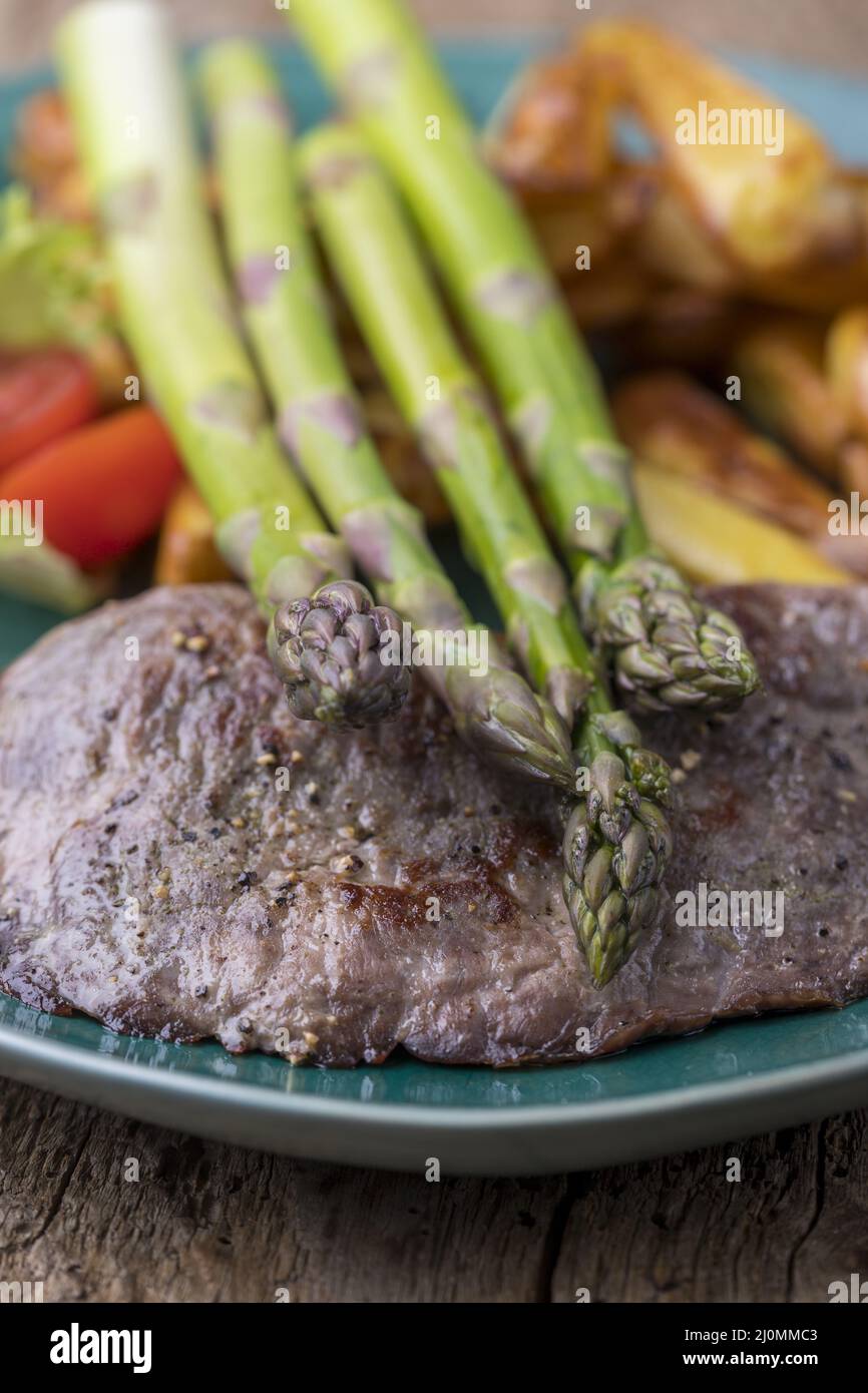 Asparagus on a grilled steak with fries Stock Photo - Alamy