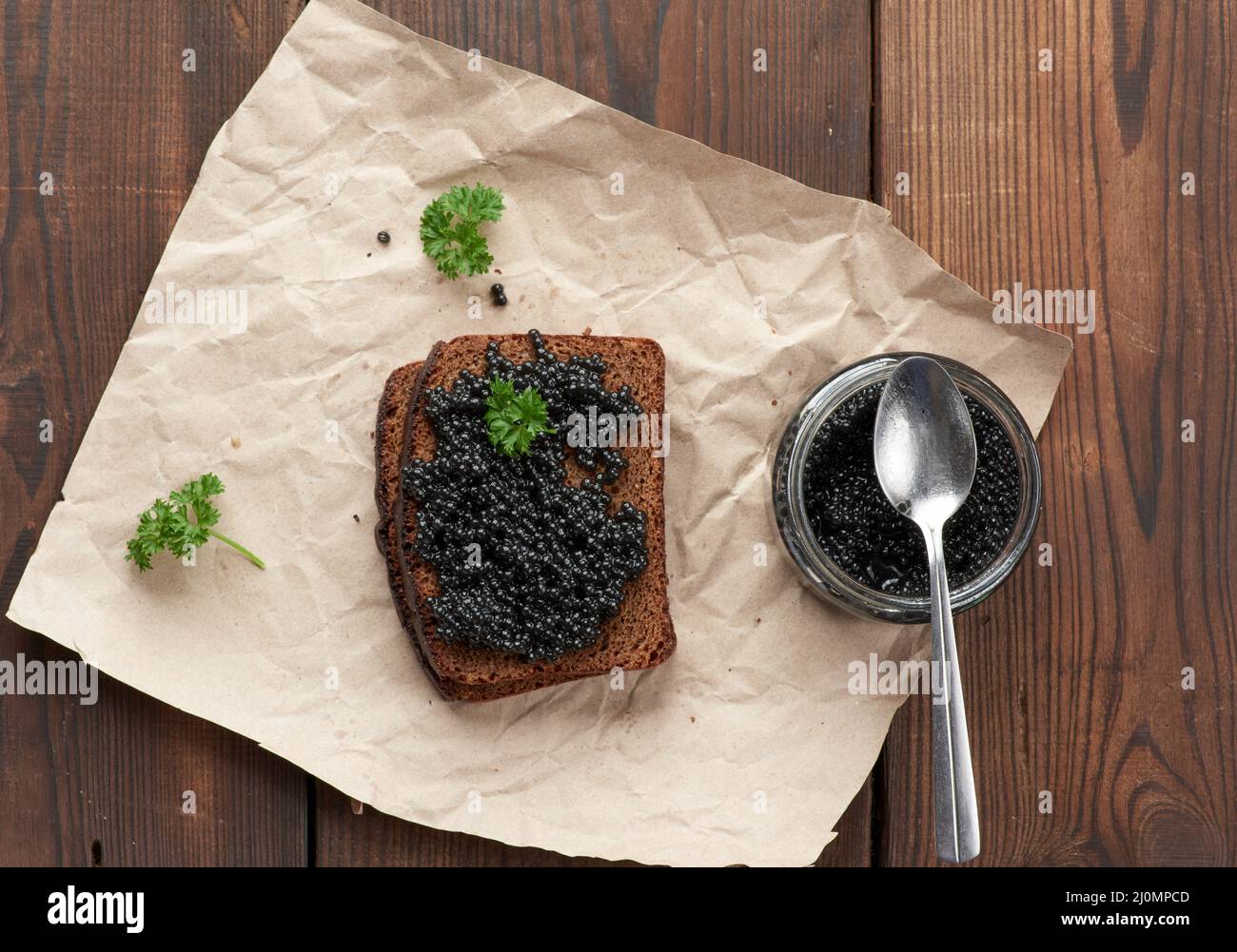 Paddlefish caviar, a slice of bread and a jar on a piece of brown paper ...