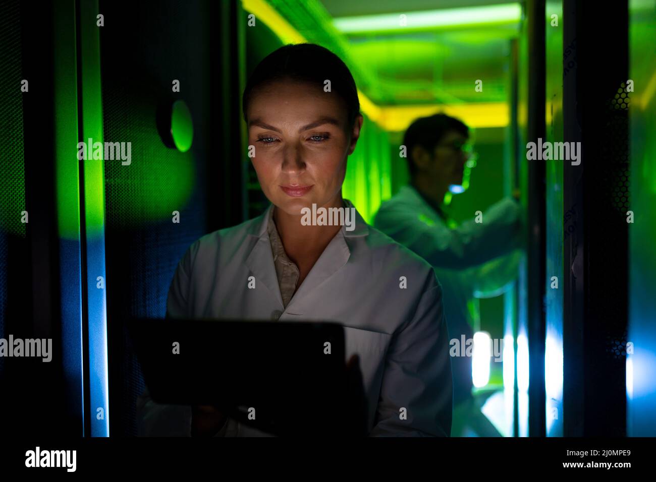 Caucasian female engineer wearing an apron using laptop in computer ...