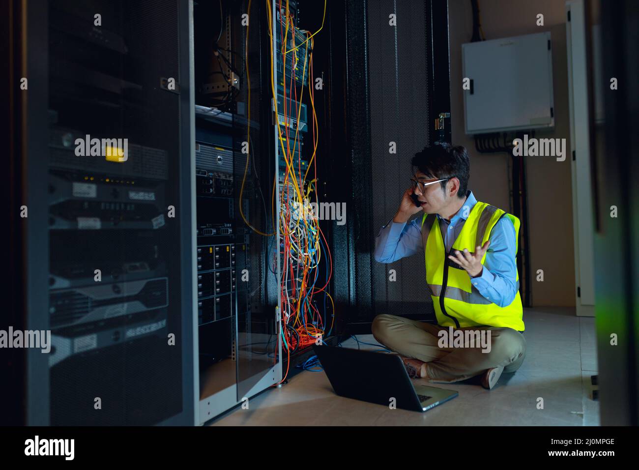 Asian male engineer with laptop talking on smartphone while inspecting ...