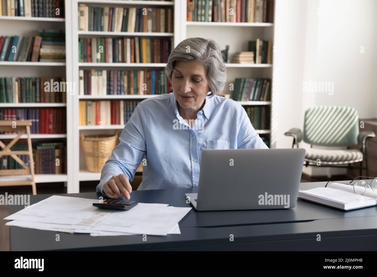 Accountant working seated at workplace desk with laptop and bills Stock ...