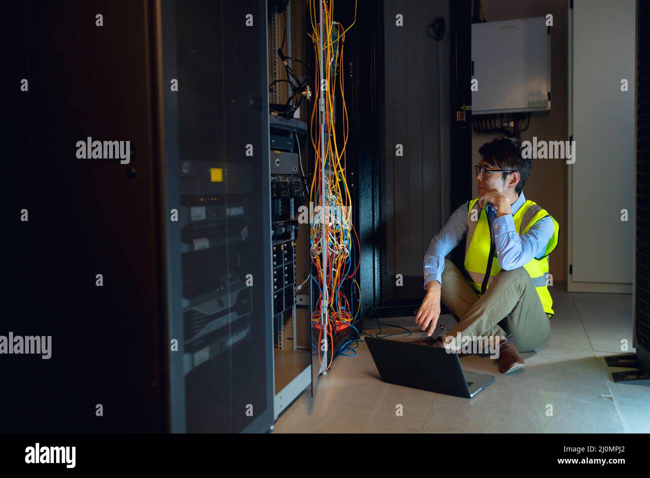 Asian male engineer wearing high visibility vest with laptop inspecting ...