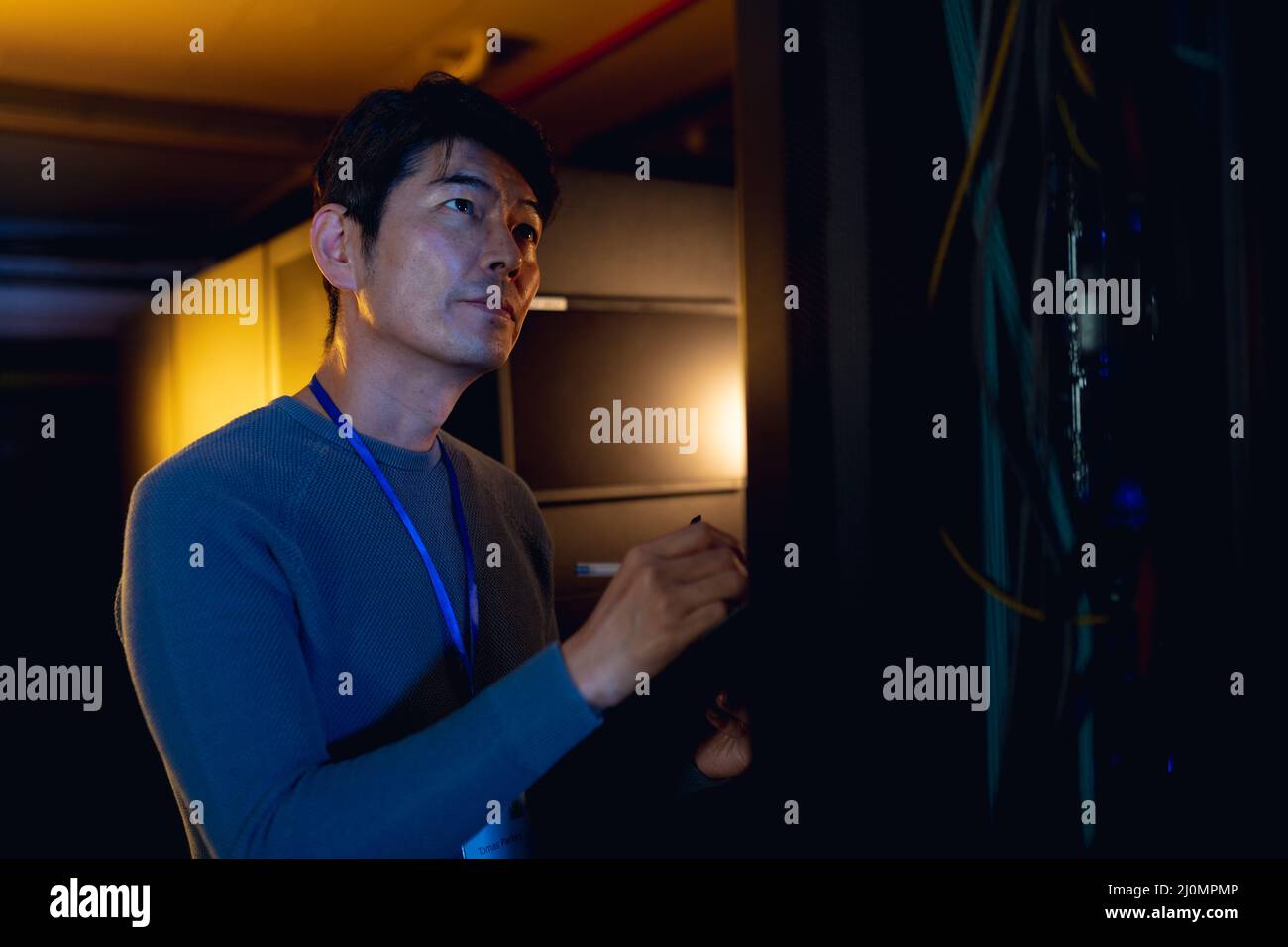 Asian male engineer writing on clipboard while inspecting in computer ...