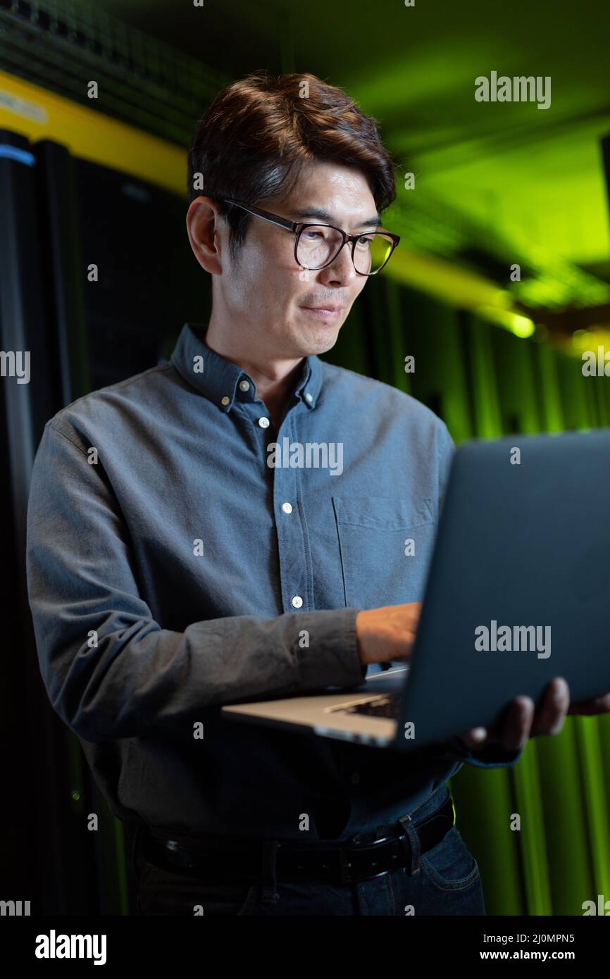 Asian male engineer using laptop in computer server room Stock Photo ...