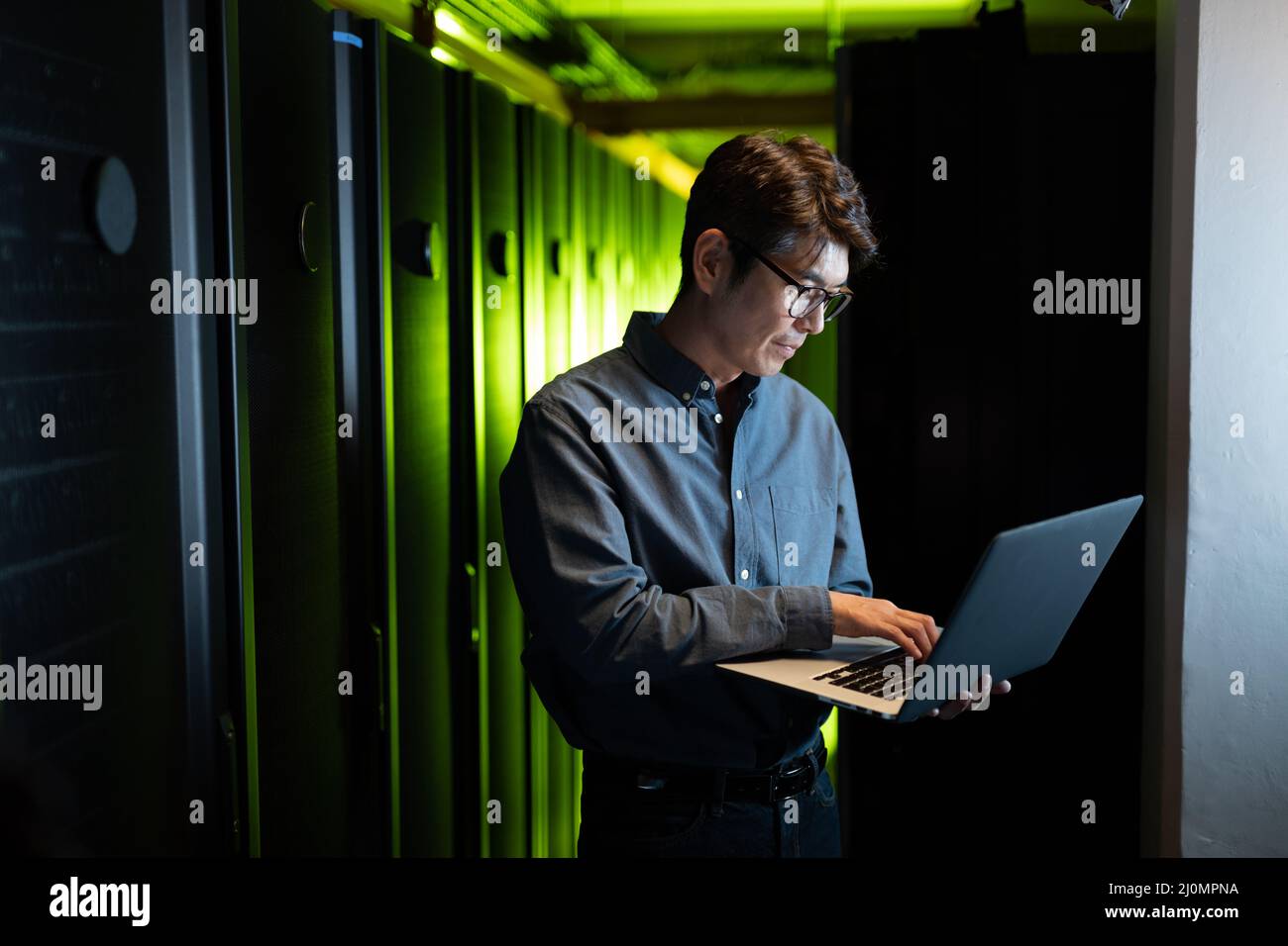 Asian male engineer using laptop in computer server room Stock Photo ...