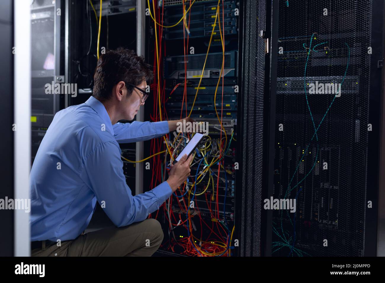 Asian Male Engineer Using Digital Tablet And Inspecting Computer Server In Computer Server Room
