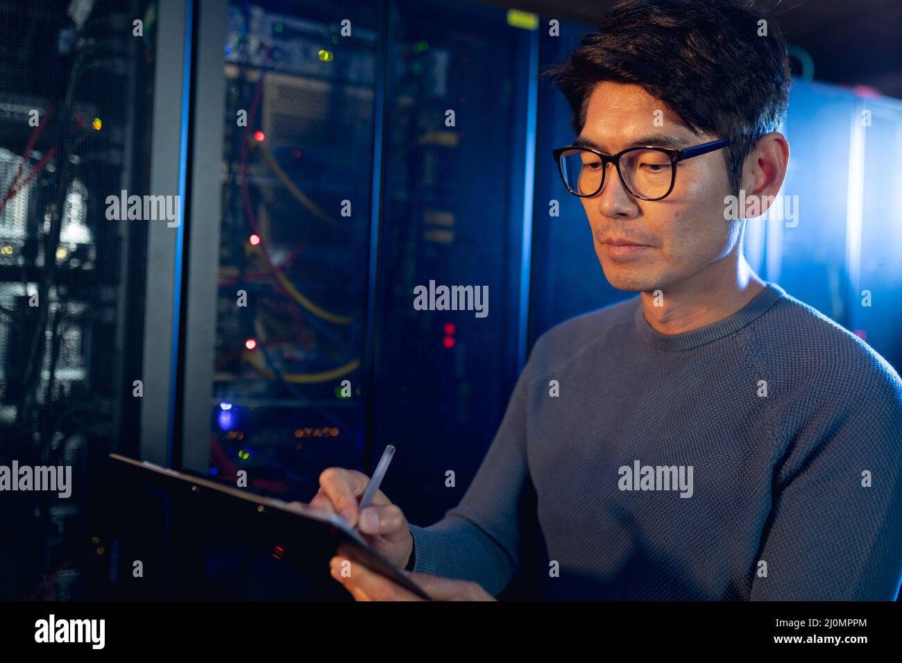 Asian male engineer writing on clipboard in computer server room Stock ...