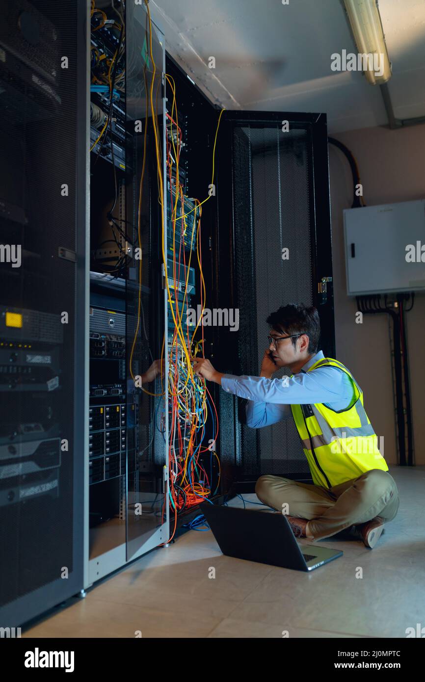 Asian male engineer with laptop talking on smartphone while inspecting ...