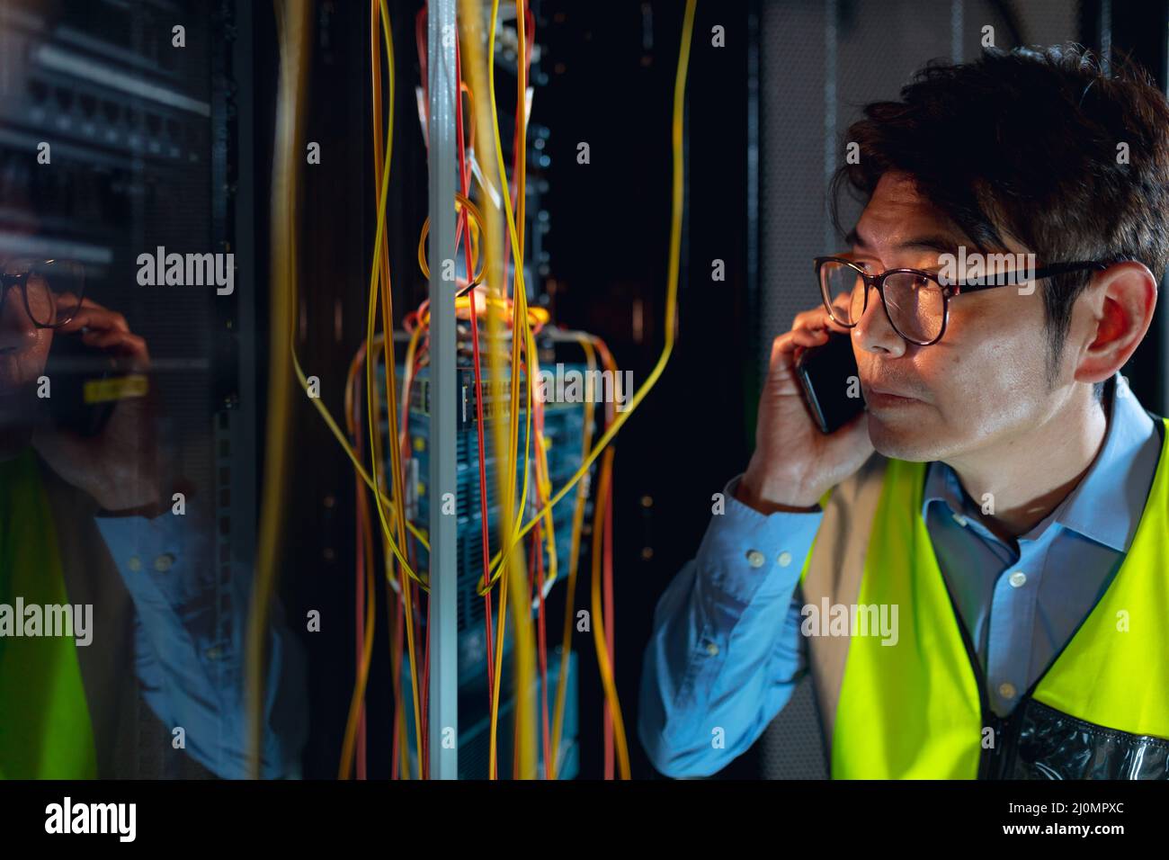 Asian male engineer talking on smartphone while inspecting in computer ...