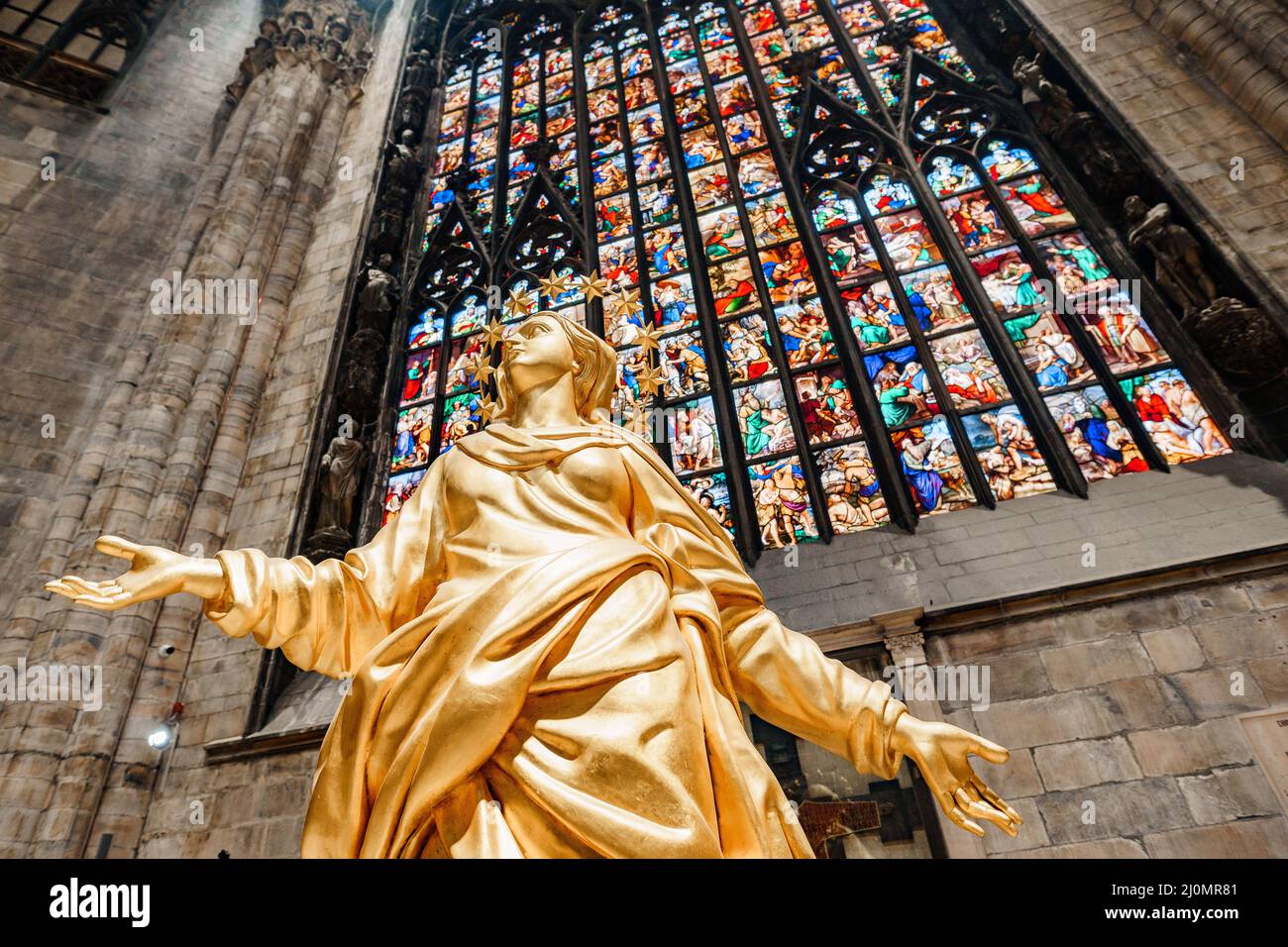 Statue of Madonna in gold against the background of a stained glass ...