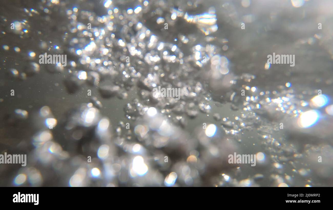 Underwater view of white and transparent air bubbles spinning and ...