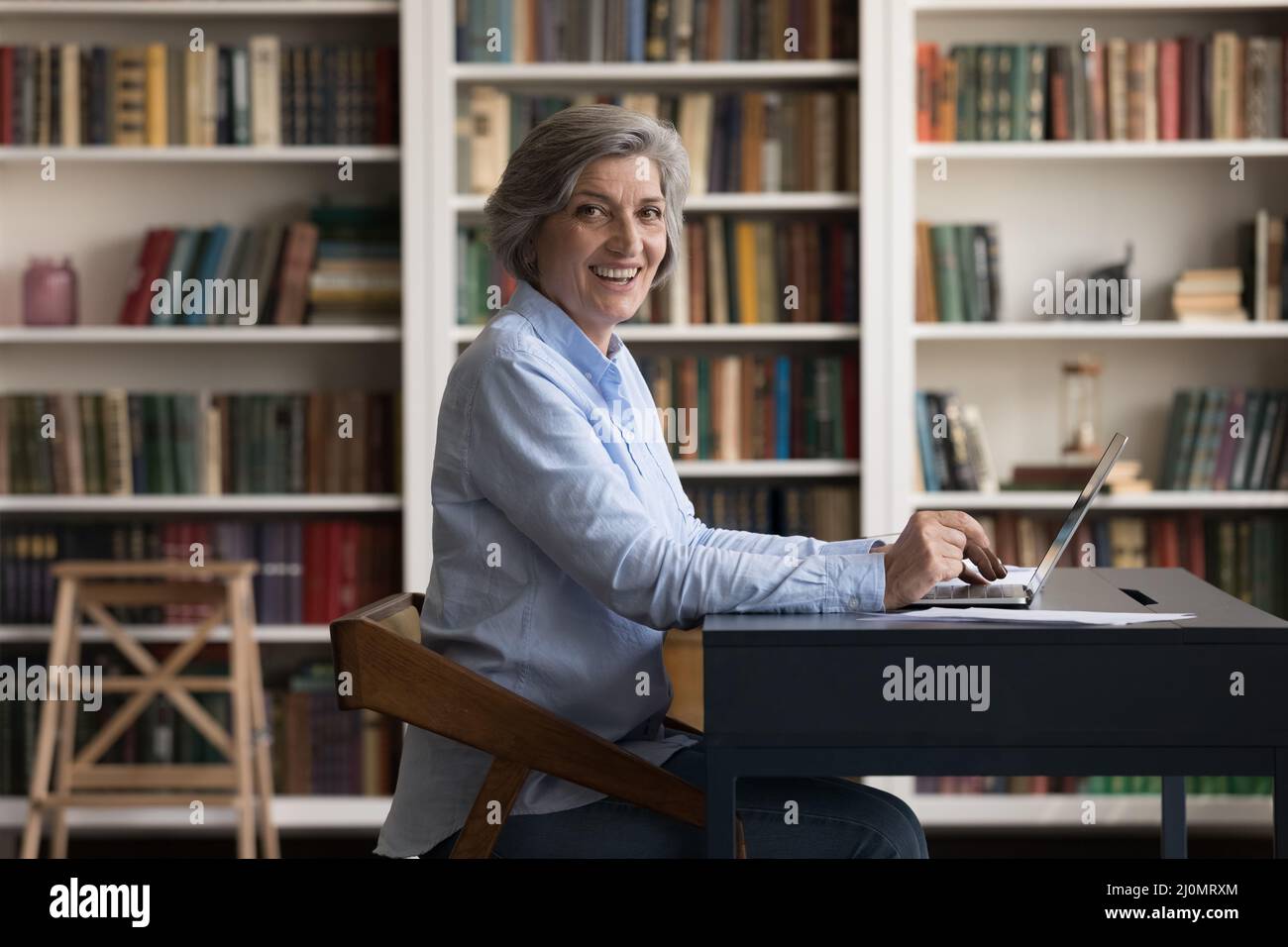 Mature businesswoman sit at desk with laptop staring at camera Stock ...