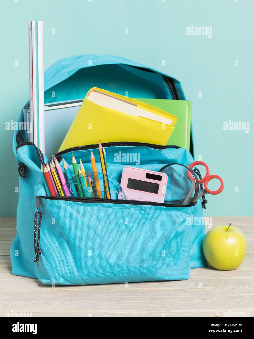 Blue school bag with essential supplies Stock Photo - Alamy