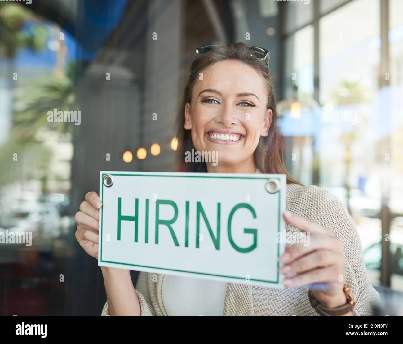 Were hiring. Portrait of a young entrepreneur holding a hiring sign in ...
