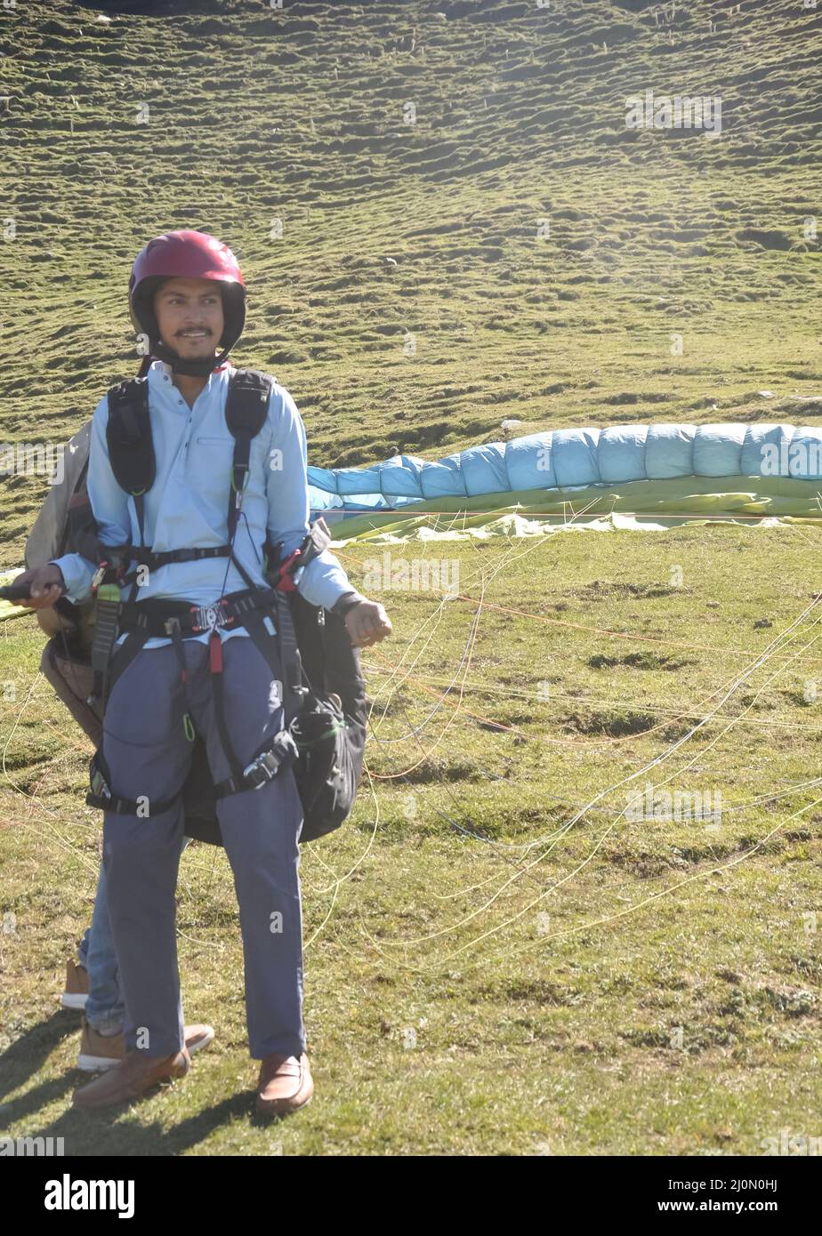 Full length of a Indian young male tourist preparing for paragliding ...