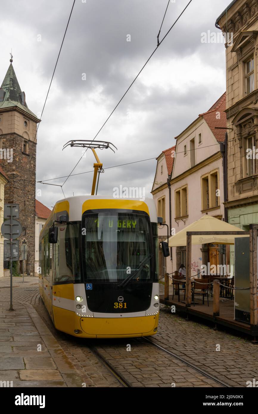 Vertical view of a yellow city tram in downtown Pilsen with historic ...
