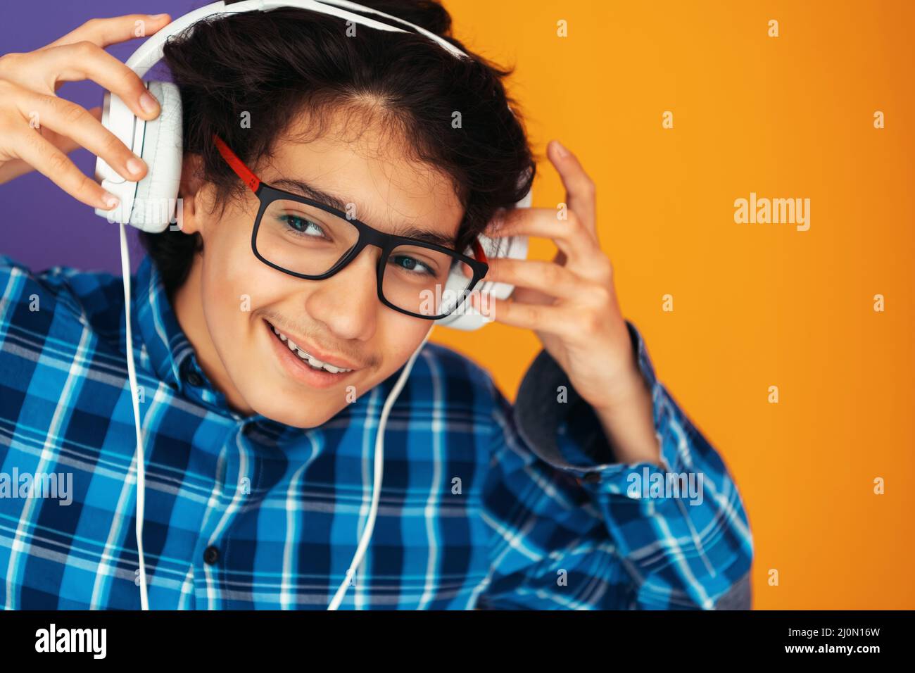 Teenage Boy Wearing Headphones And Listening To Music purple background ...