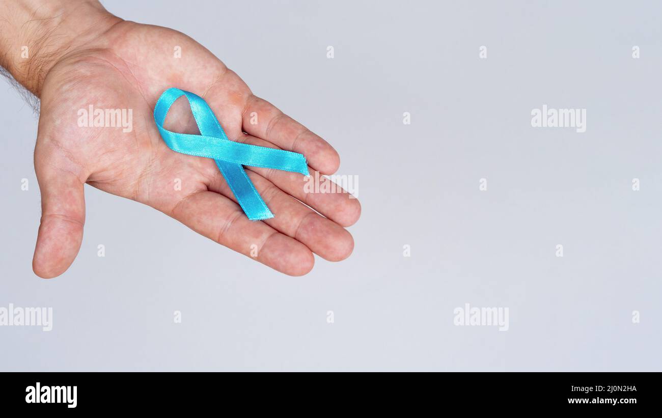 Close up hand holding blue ribbon Stock Photo - Alamy