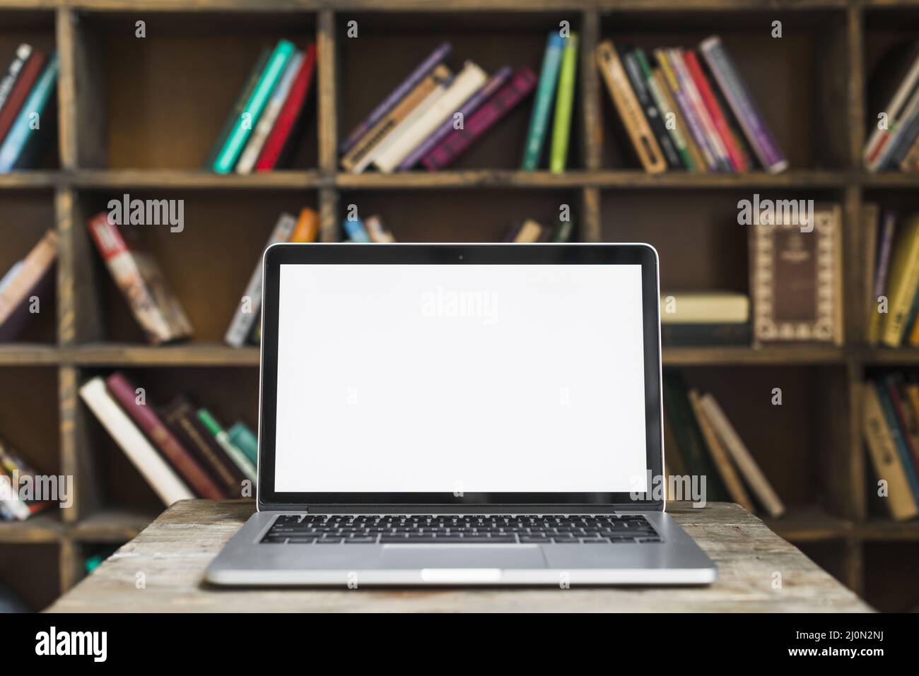Blank screen open laptop wooden desk library Stock Photo - Alamy