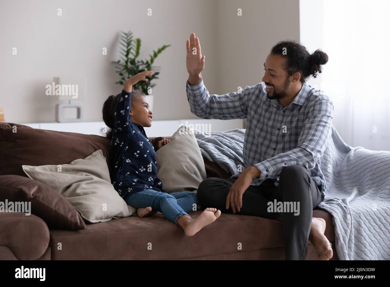 Happy dad and little girl giving high five on couch Stock Photo - Alamy