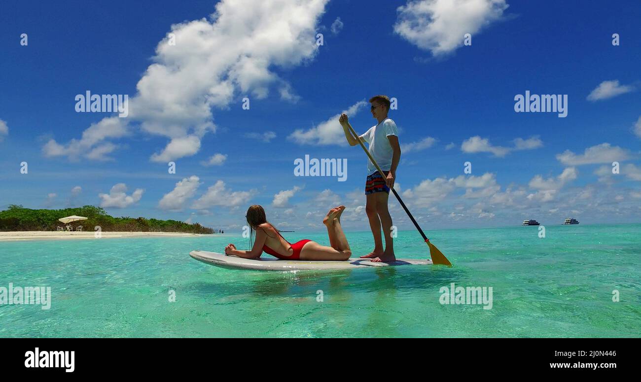 A Caucasian couple boarding on a paddleboard in Rasdhoo Island, The ...