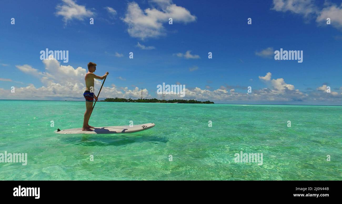 Caucasian man boarding on a paddleboard in Rasdhoo Island, The Maldives ...