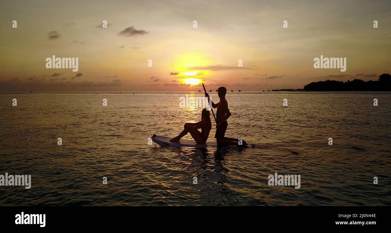 Caucasian couple boarding on a paddleboard in Rasdhoo Island, The ...