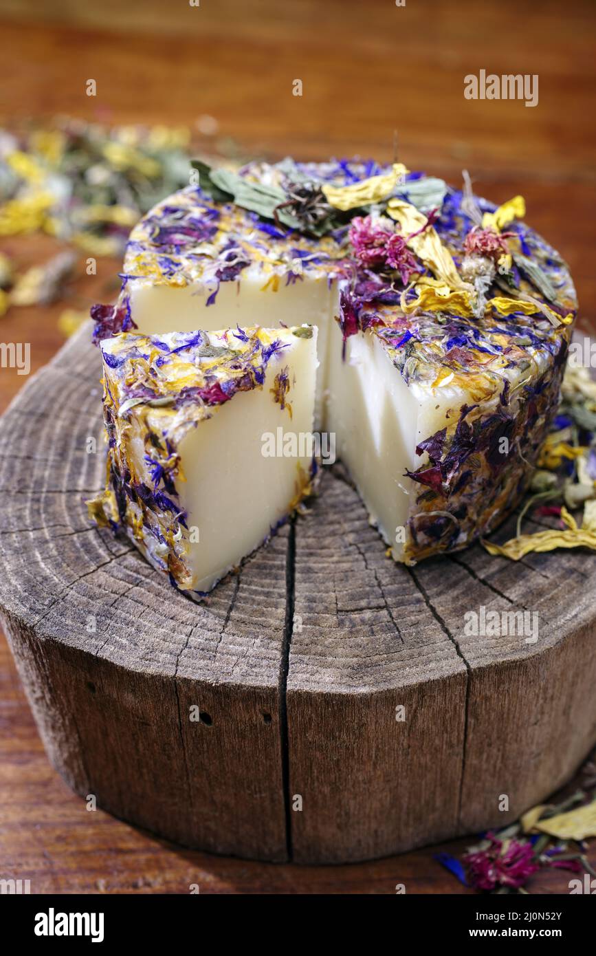 Traditional aged alpine cheese with herb flowers of the Alps offered as ...