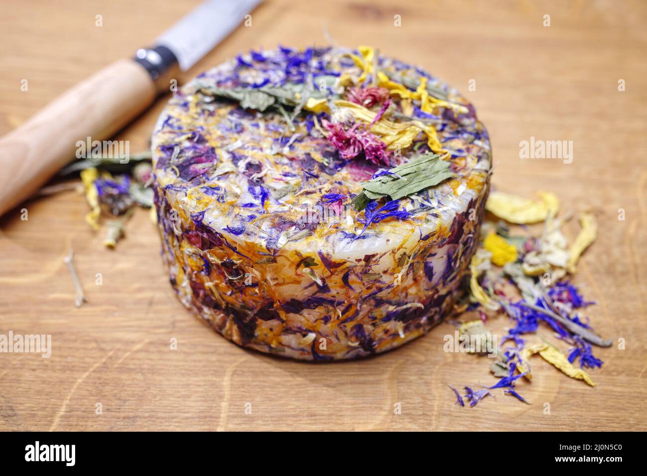 Traditional aged alpine cheese with herb flowers of the Alps offered as ...