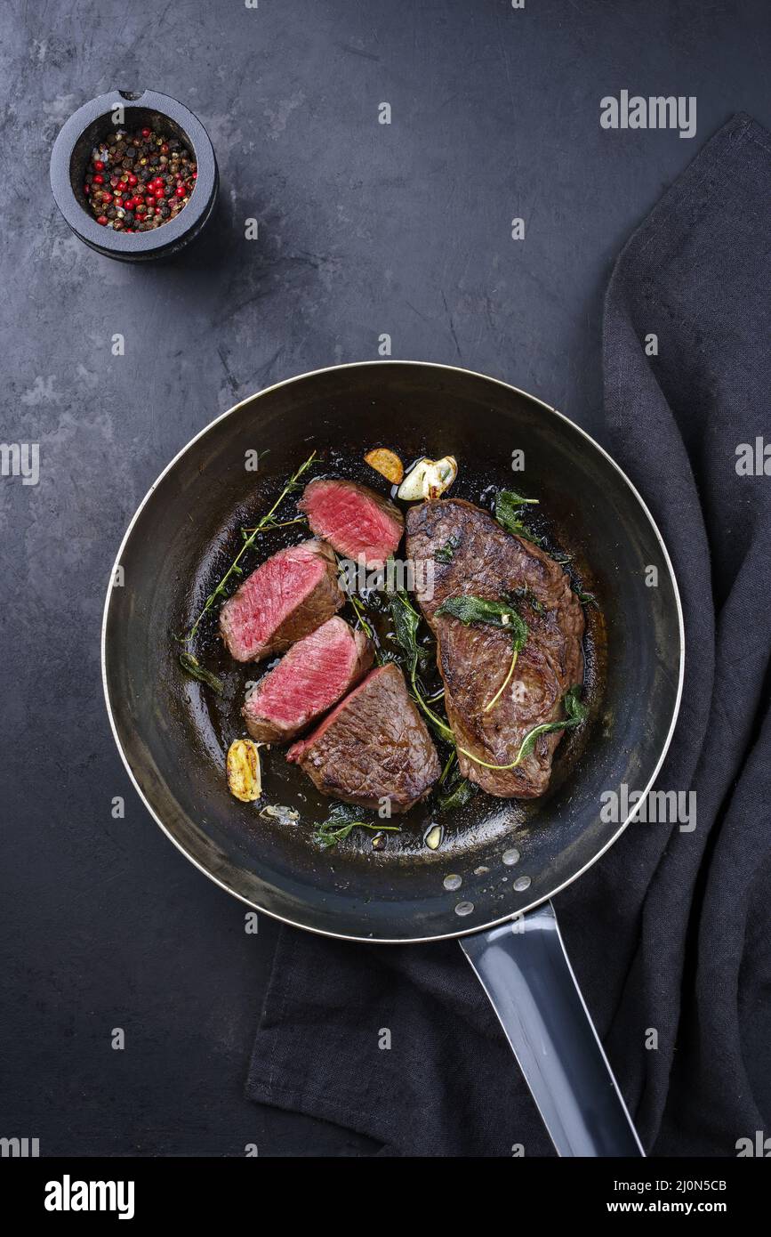 Traditional fried dry aged bison beef rump steaks with herbs and garlic ...