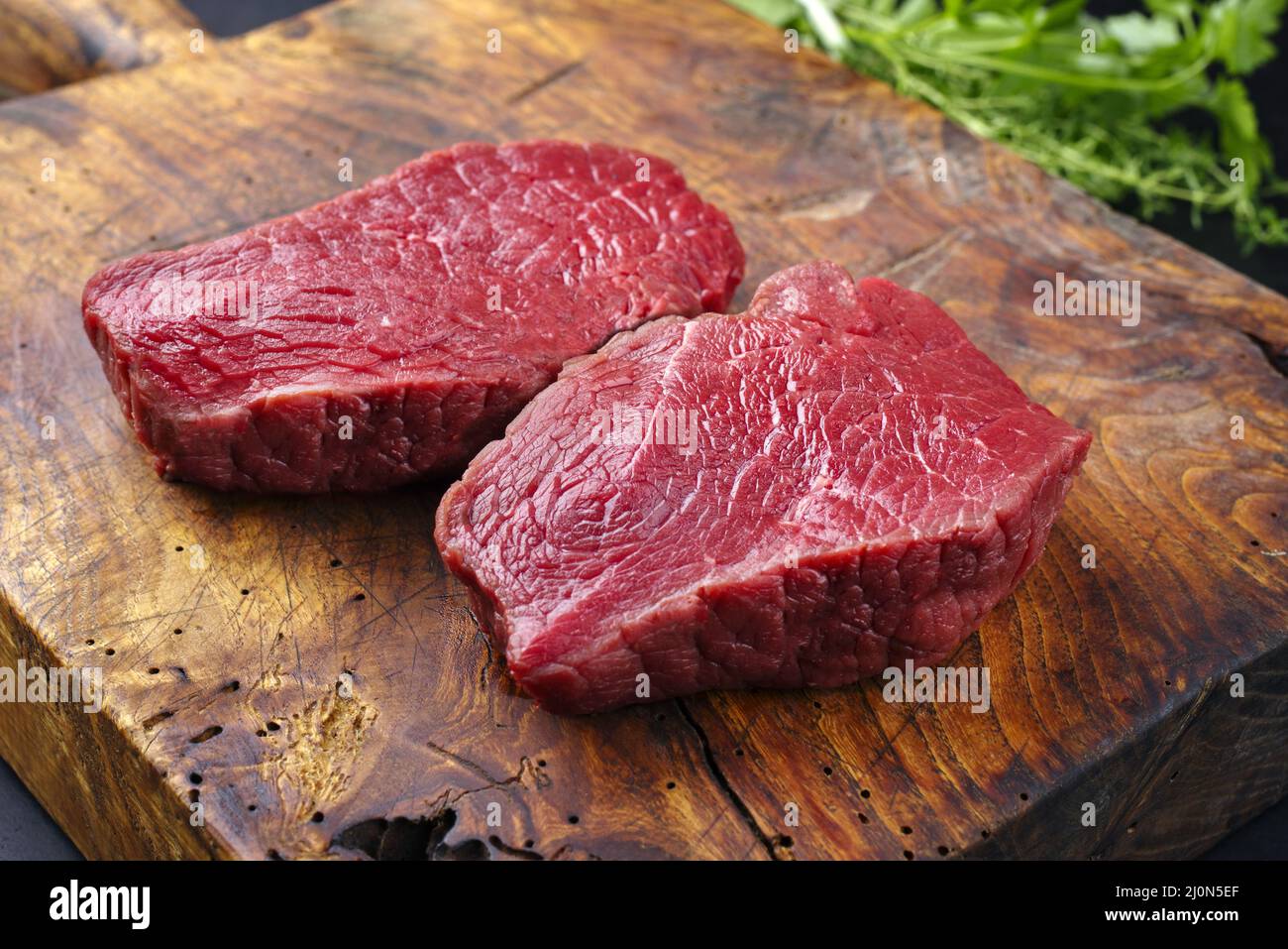 Raw dry aged bison beef rump steaks as top view with herbs on a rustic ...