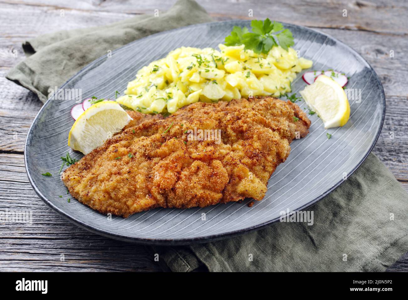 Traditional deep-fried schnitzel with potato salad and lemon slices ...