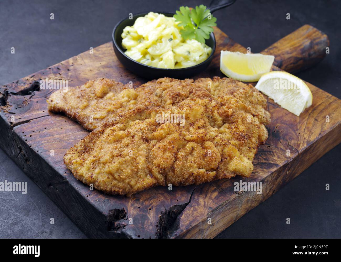 Traditional deep-fried schnitzel with potato salad and lemon slice ...