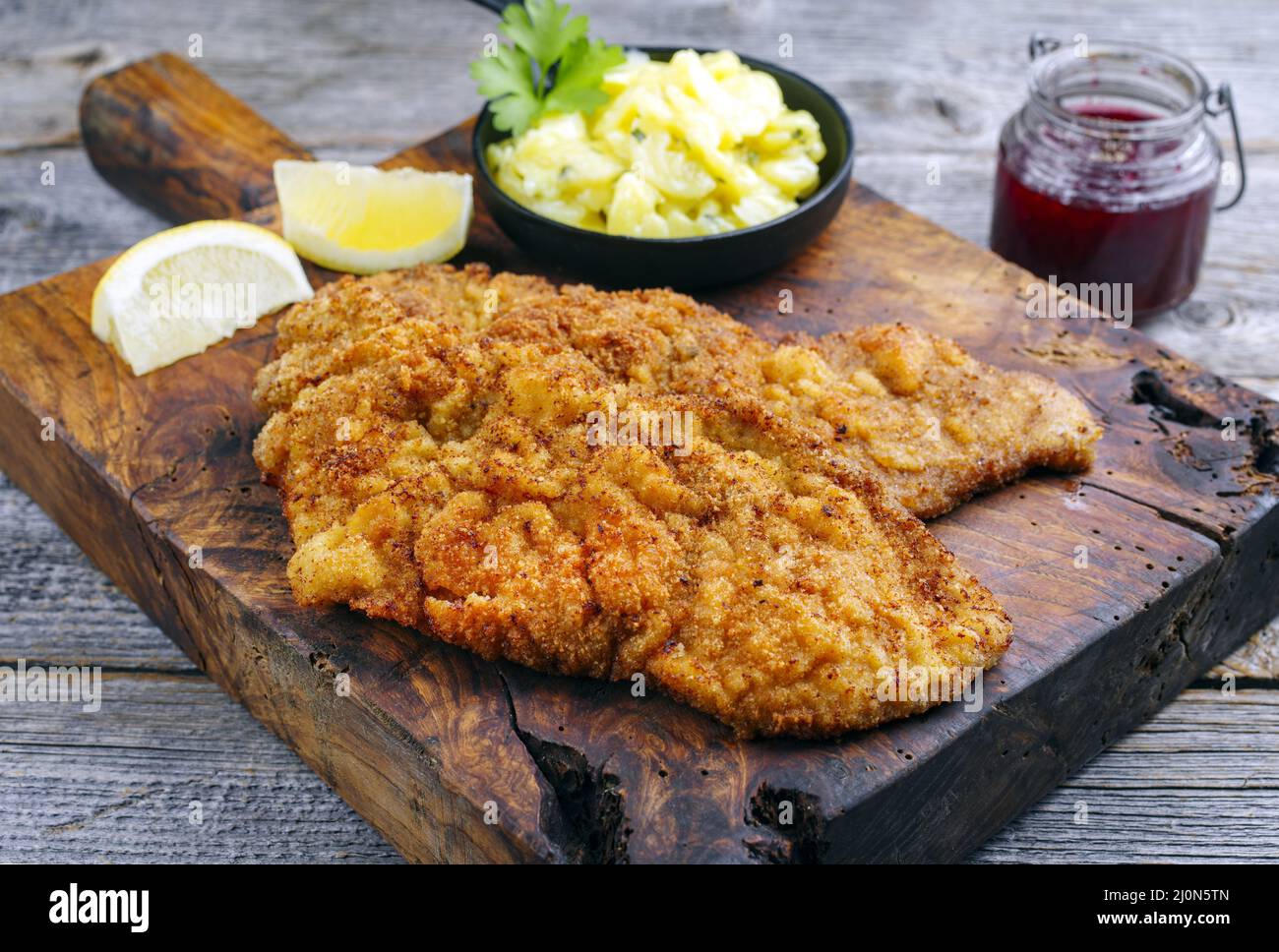 Traditional deep-fried schnitzel with potato salad and cranberries ...