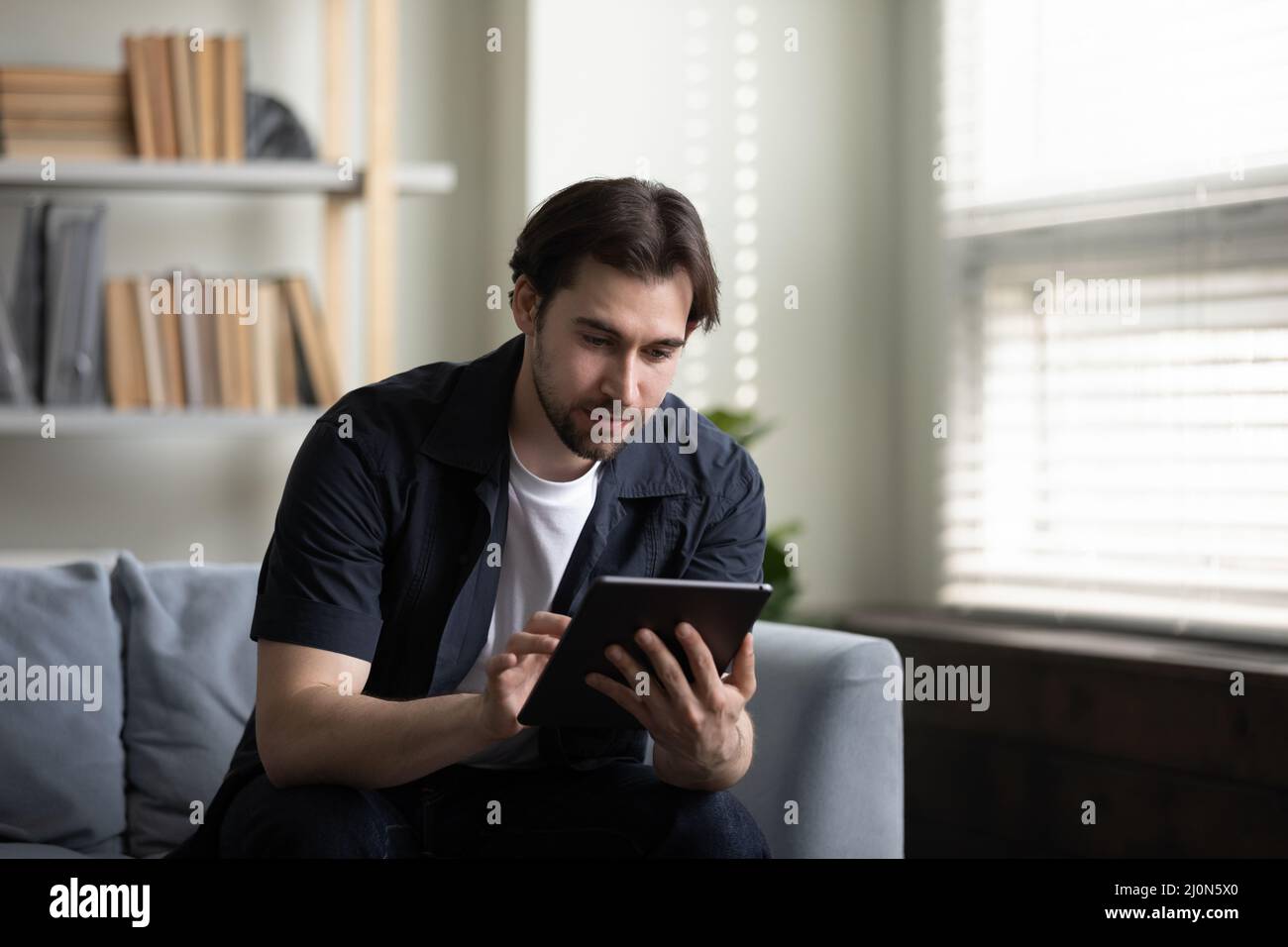 Focused tablet user man browsing internet, using online application ...