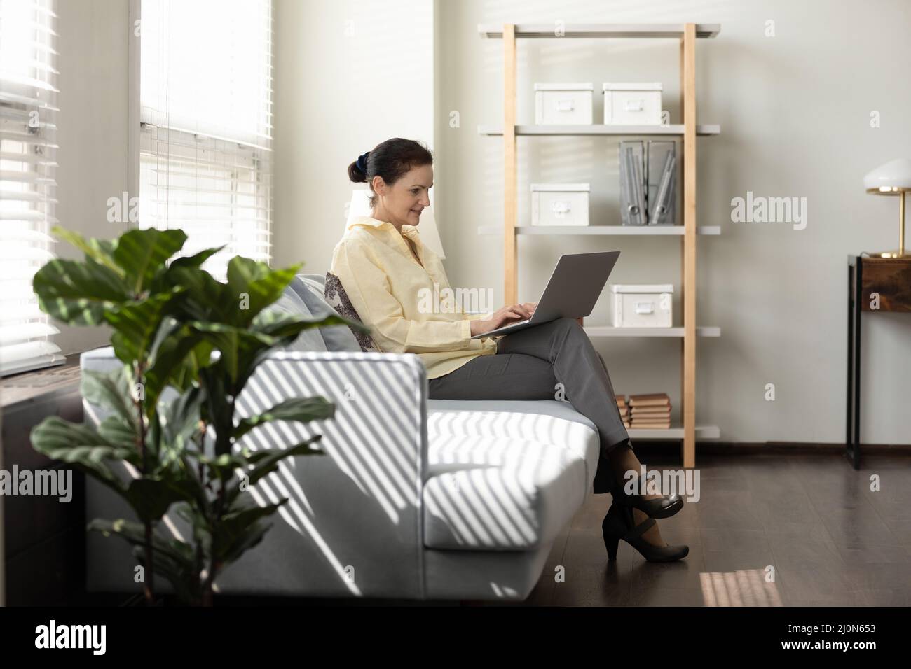 Positive mature business lady sitting on couch in office Stock Photo - Alamy