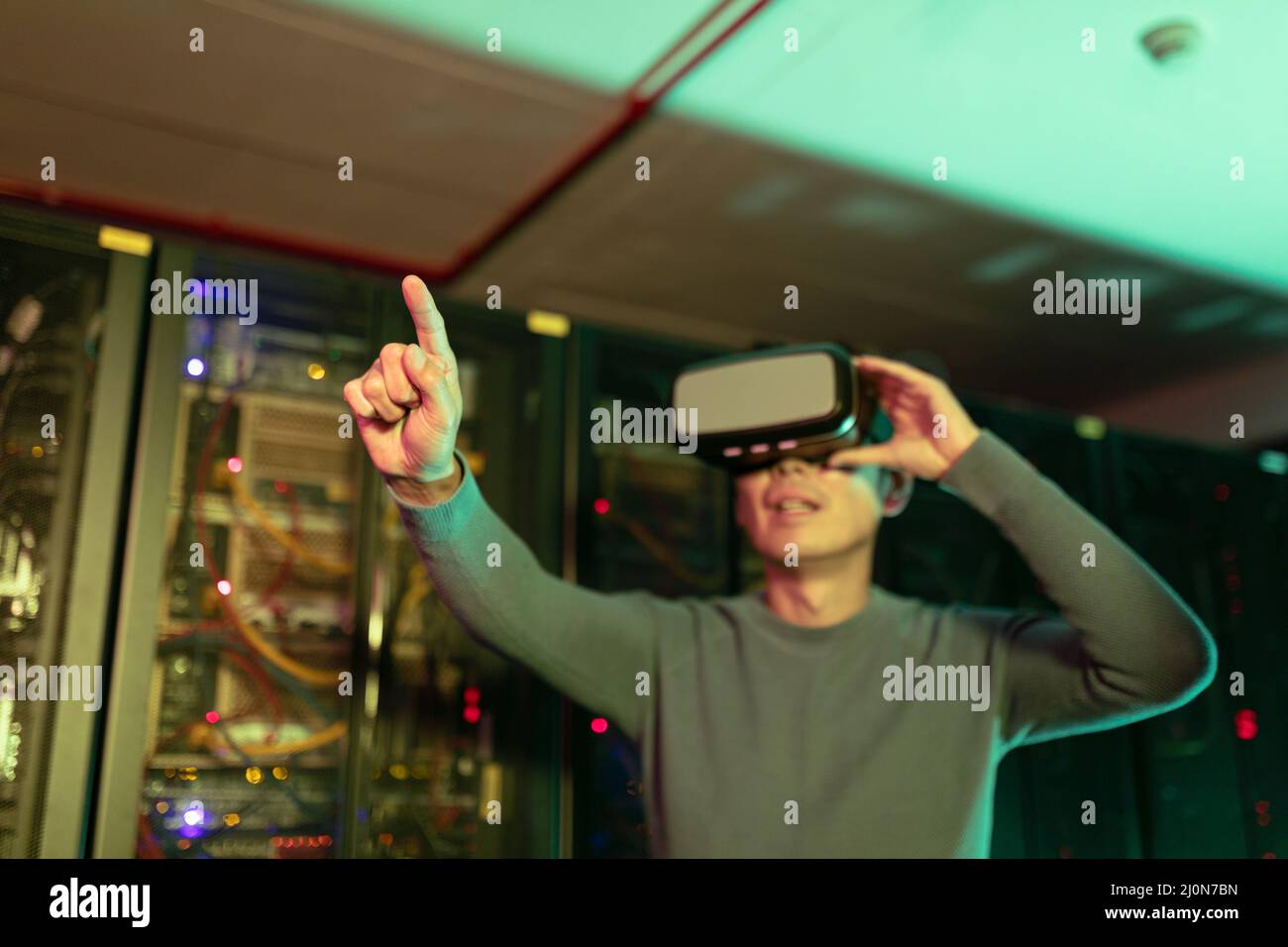 Asian man wearing vr headset touching an invisible screen in computer ...