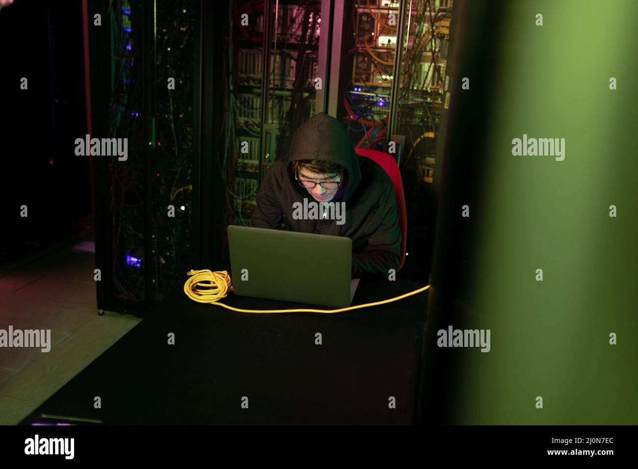 Asian male hacker using a laptop in computer server room Stock Photo ...
