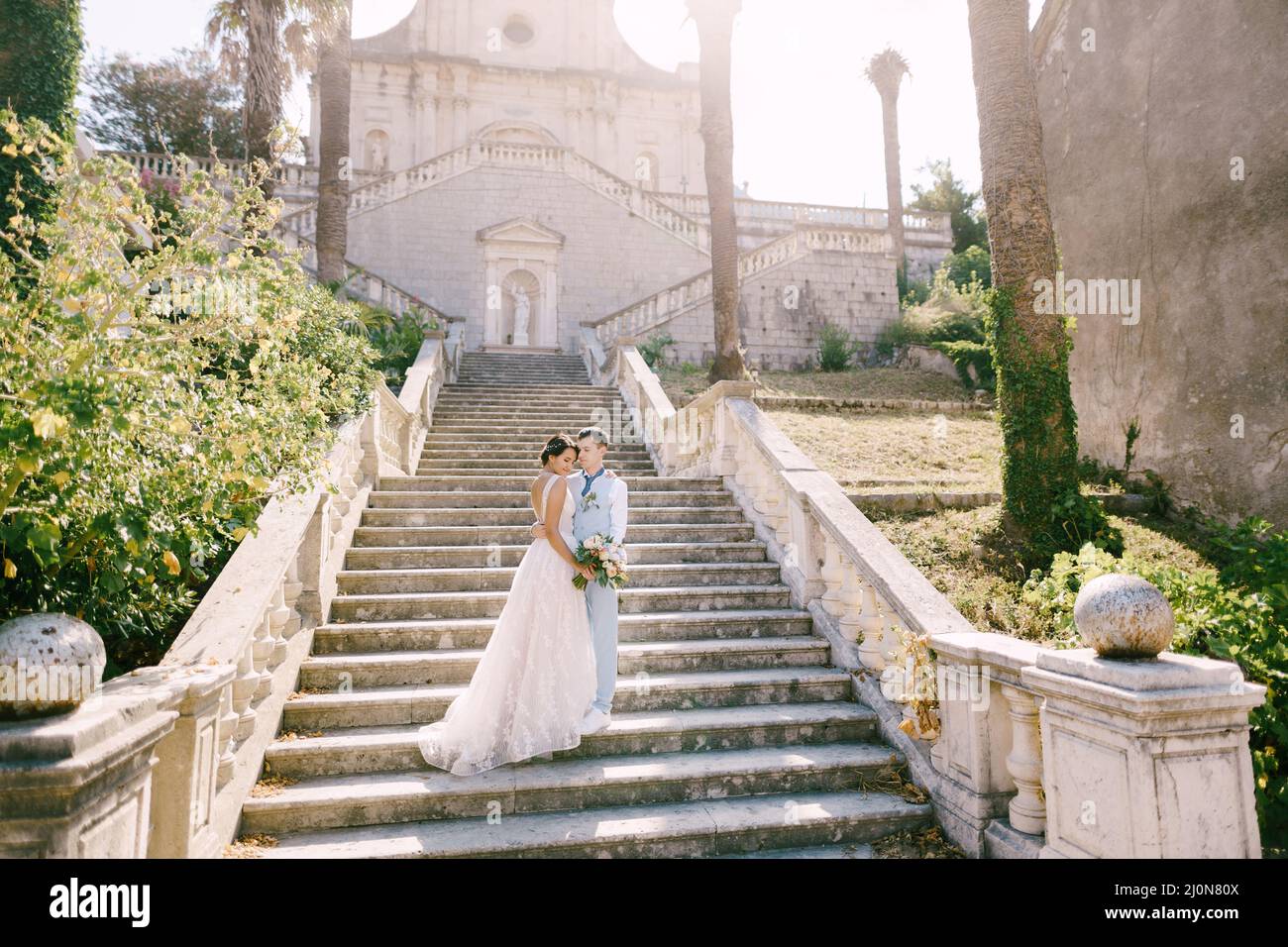 The bride and groom stand hugging on the stairs of the Nativity of the ...