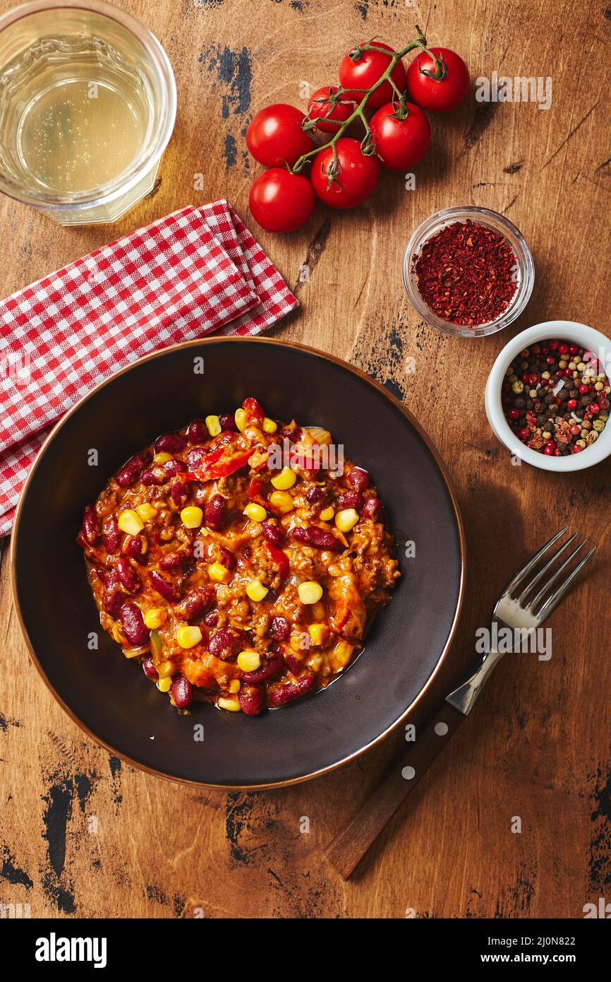 Chili Con Carne with ground beef, beans and corn in dark bowl on wooden ...