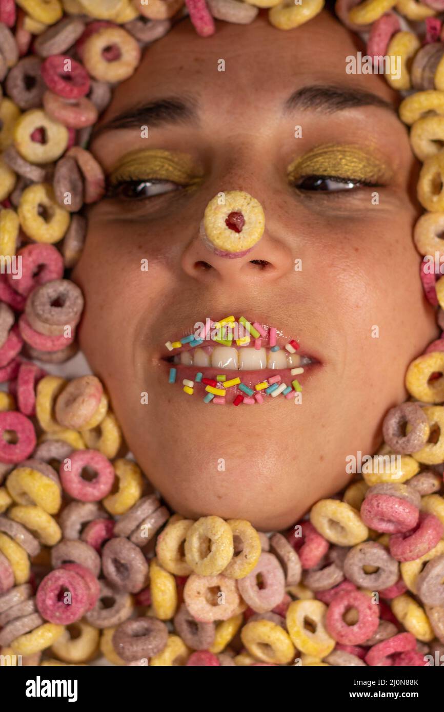 Vertical shot of a Caucasian woman's face surrounded by sugary cereals ...