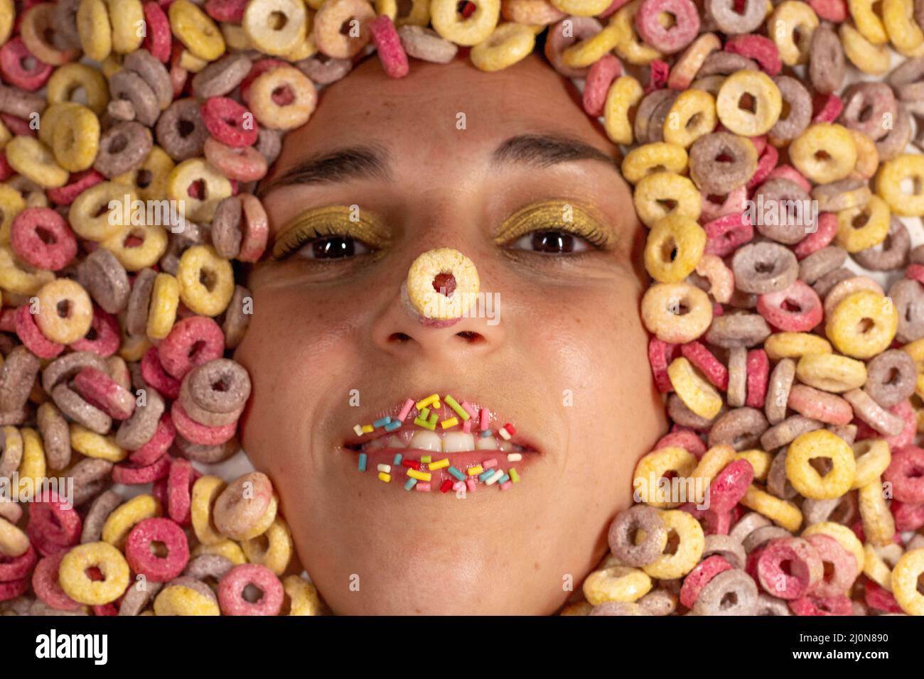 Caucasian woman's face surrounded by colored sugary cereals and candies ...