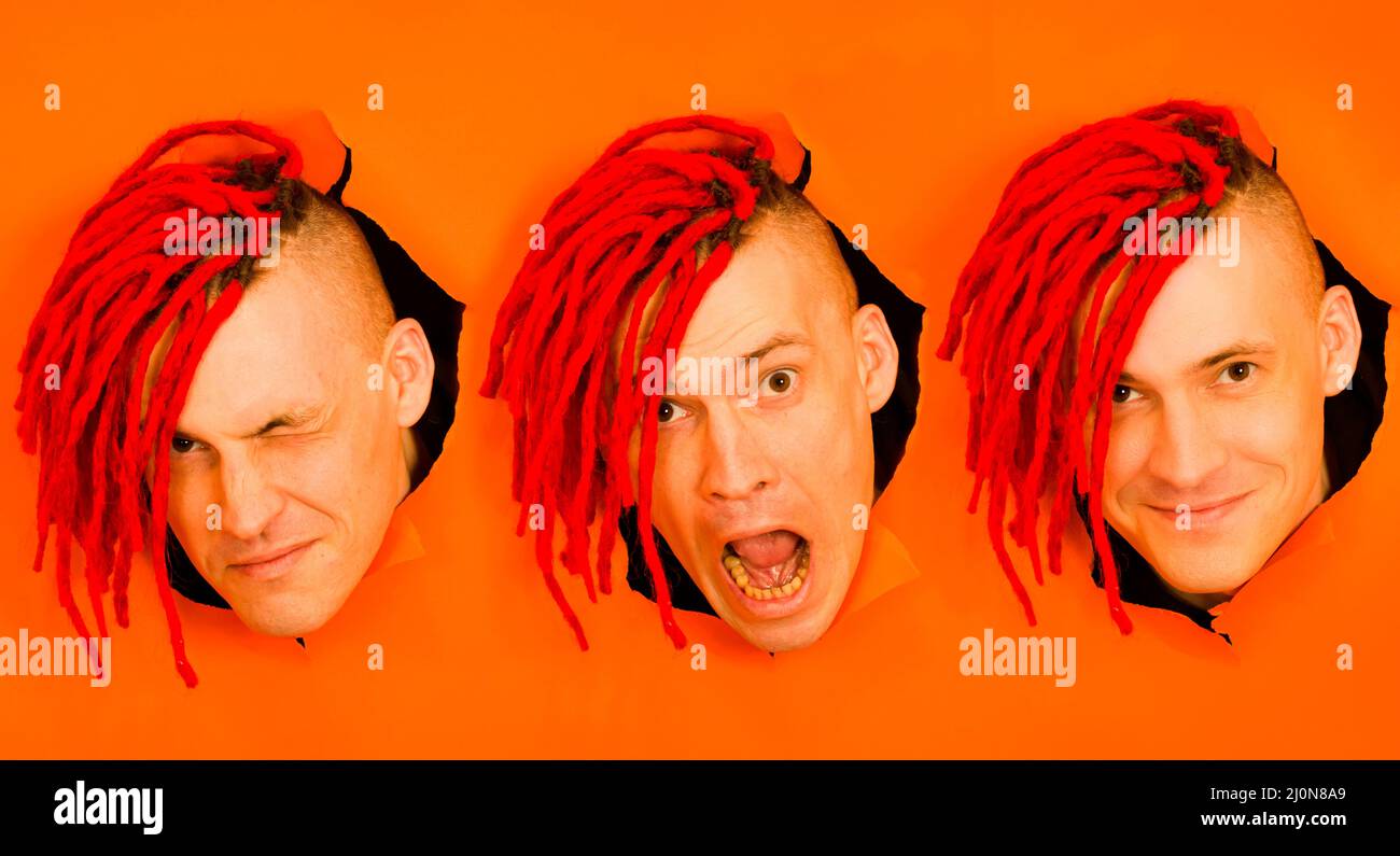 Funny male with red dreadlocks peeking through torn orange paper ...