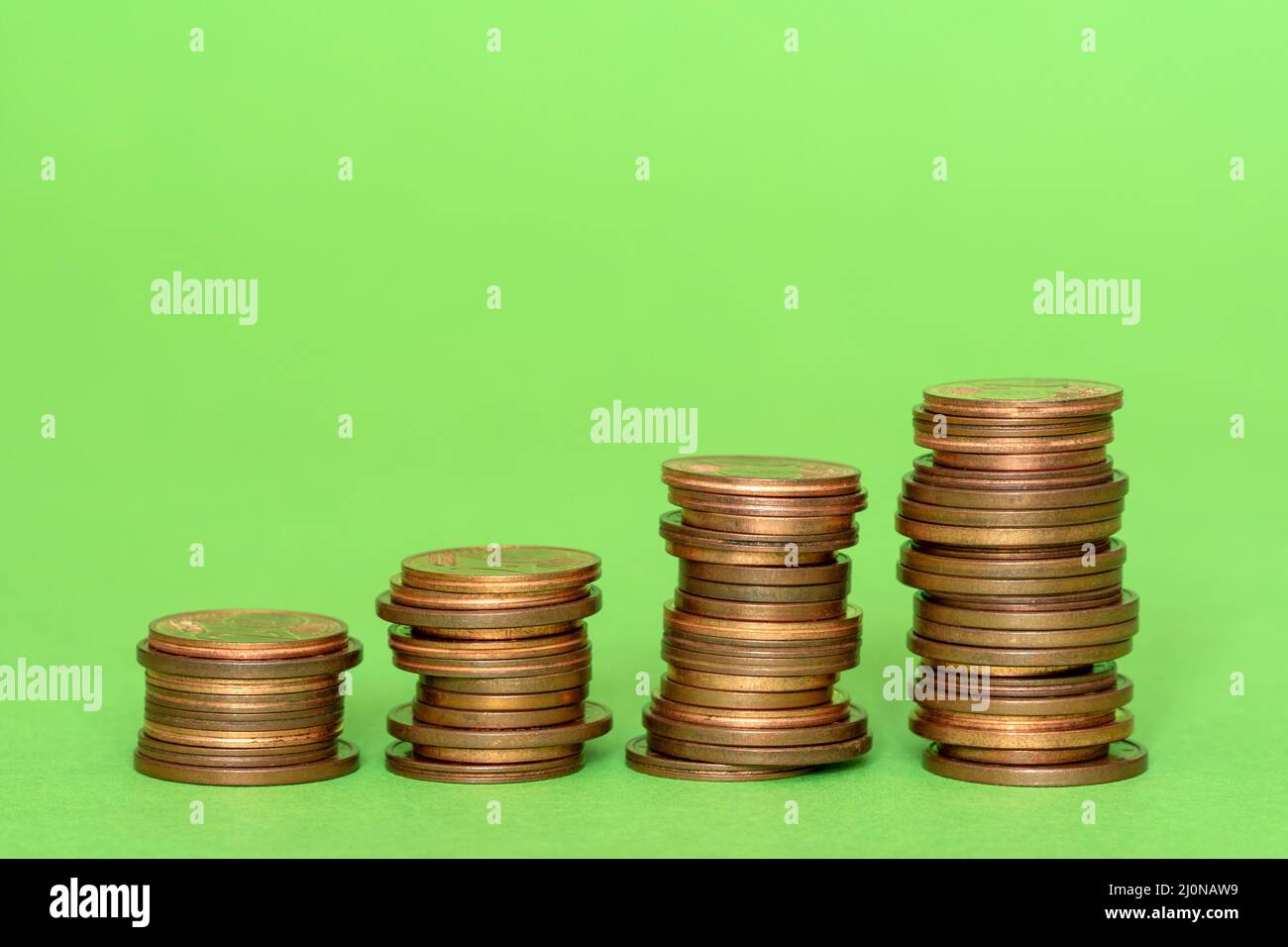Coin stacks on a green background Stock Photo - Alamy