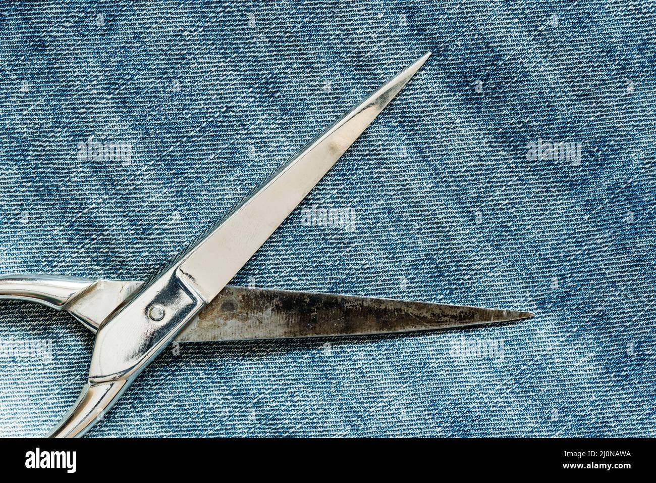 Scissors on the blue jeans background Stock Photo - Alamy