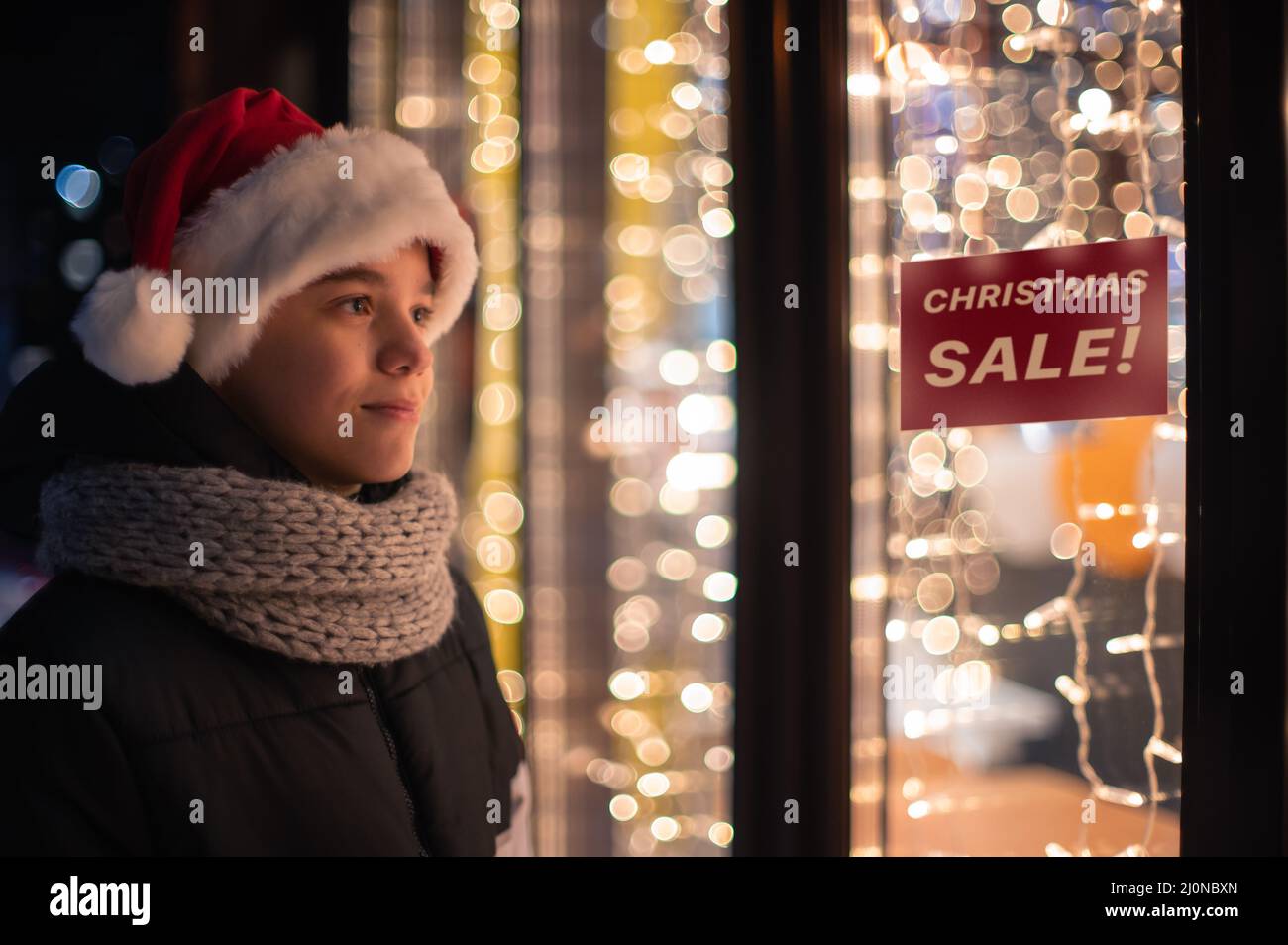 Boy in Santas hat looking in shop window Stock Photo - Alamy