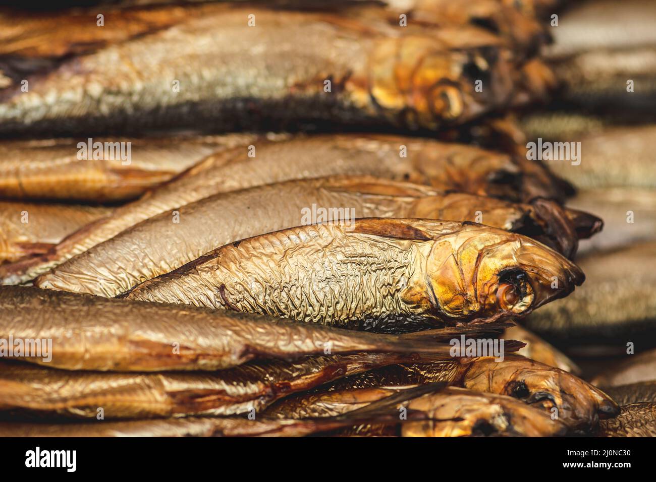Dry smoked salted herrings in a row in a regional street food market ...