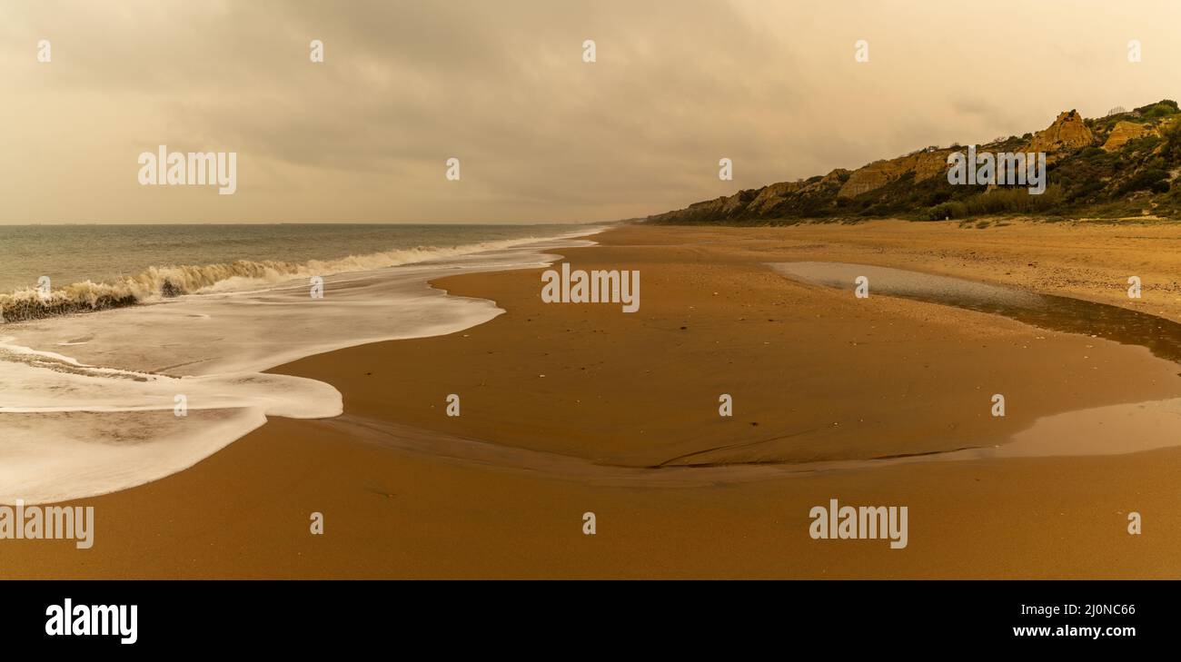 A panorama view of a beautiful long and empty beach with shore break ...