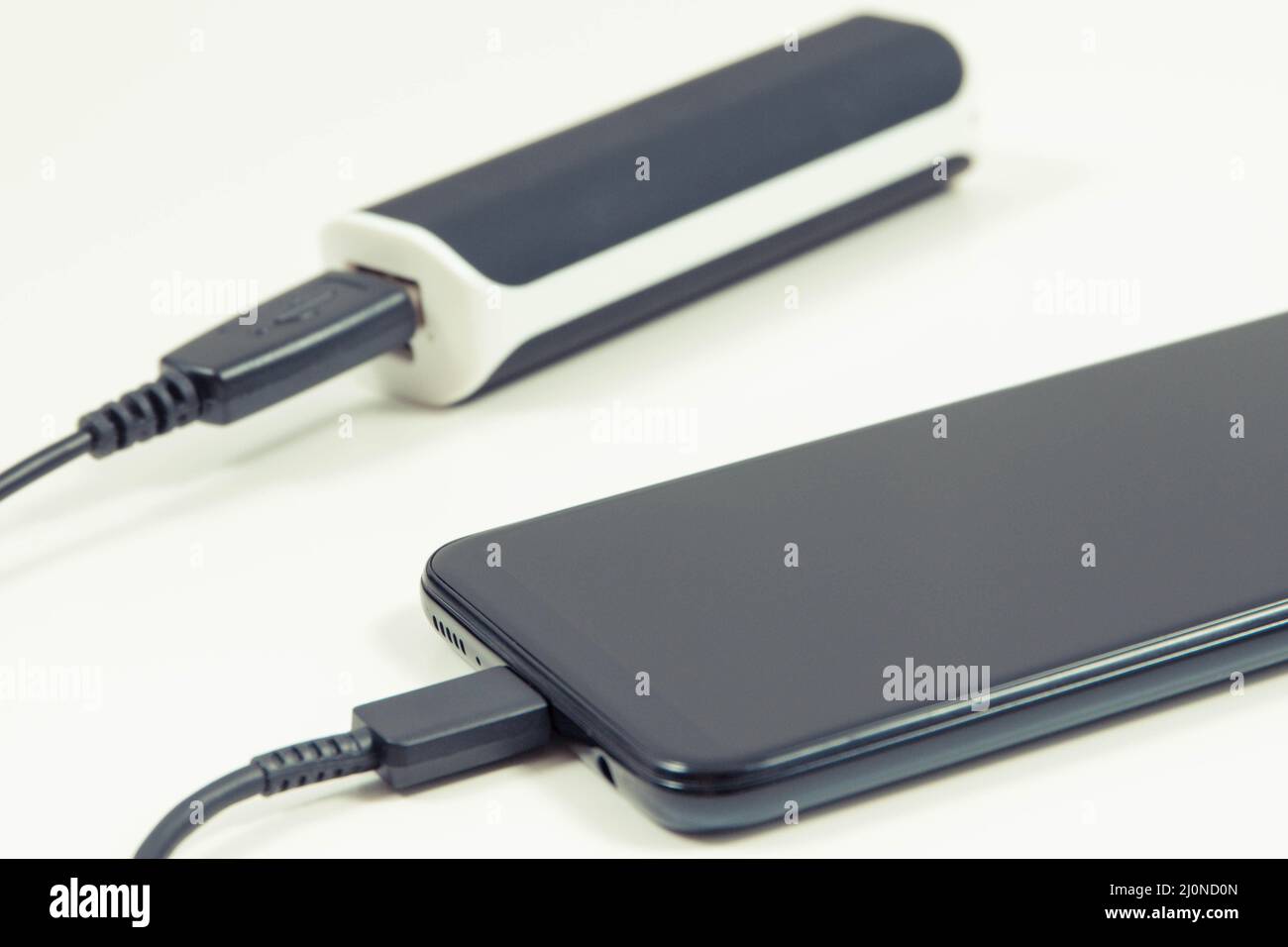 Smartphone with connected plug of powerbank. Telephone charging. White ...